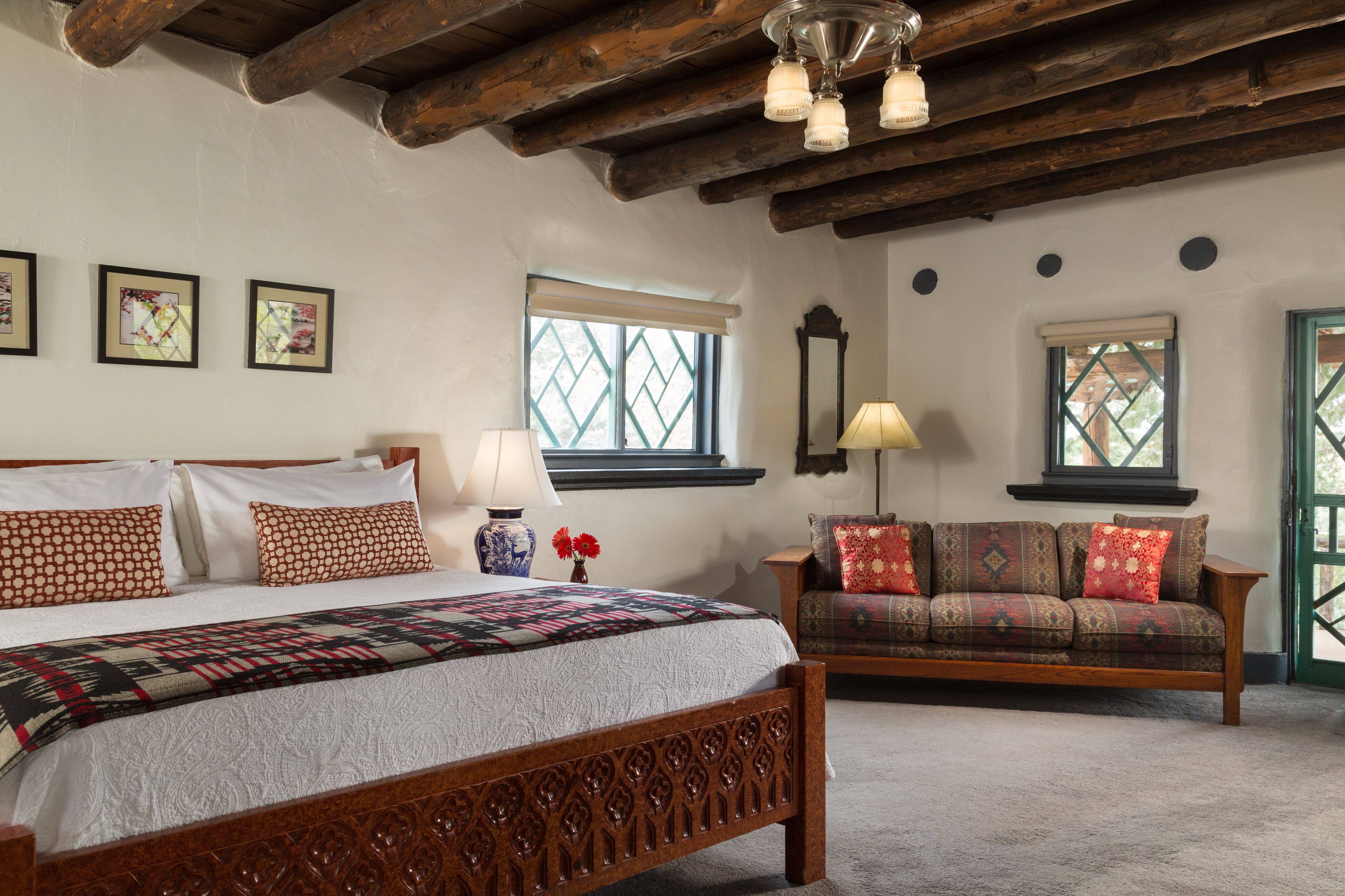 Quarto com cama de madeira, sofá e janela com vista.