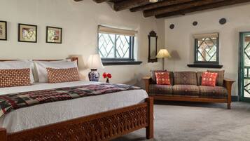 Quarto com cama de madeira, sofá e janela com vista.
