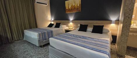 Quarto de hotel com duas camas, um quadro grande na parede e um aparelho de ar condicionado.