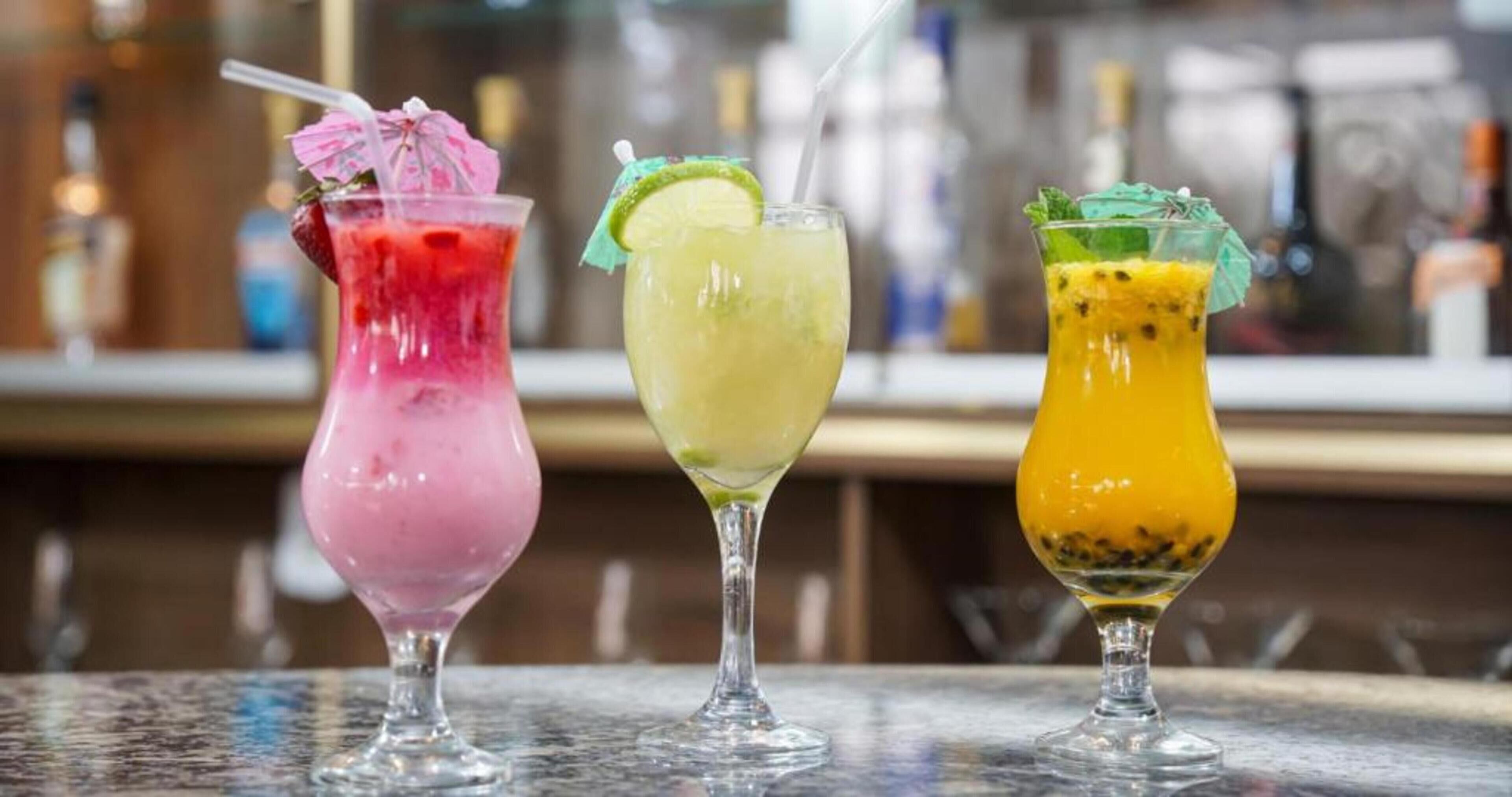 Três coquetéis coloridos em um balcão de bar.