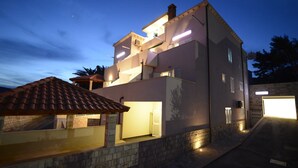 Uma casa moderna de dois andares com telhado plano, varanda e garagem.