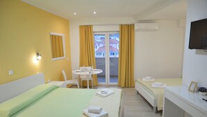 Quarto de hotel com duas camas, uma escrivaninha, uma cadeira, uma mesa e uma televisão.