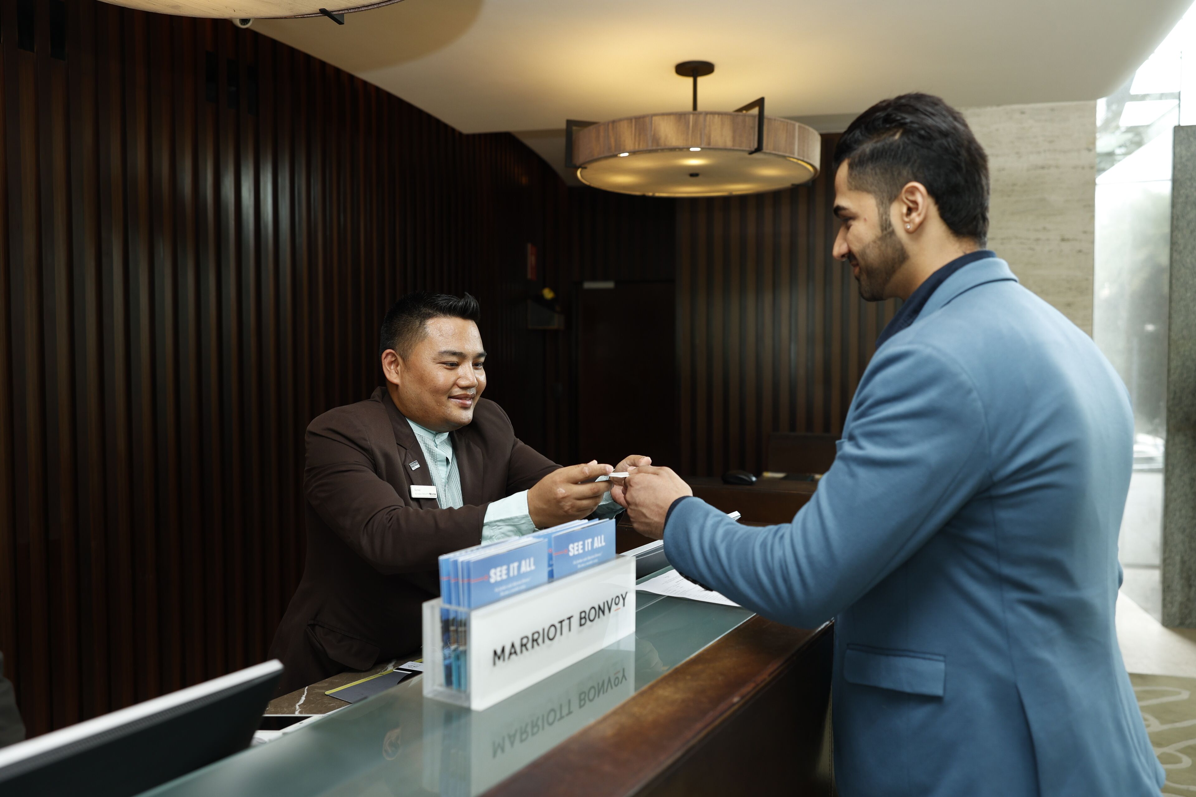 Bancada de recepção de hotel com uma placa indicando "Marriott Bonvoy" e uma plaqueta com o nome "Yashasvi Tiwari".