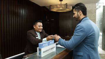 Bancada de recepção de hotel com uma placa indicando "Marriott Bonvoy" e uma plaqueta com o nome "Yashasvi Tiwari".