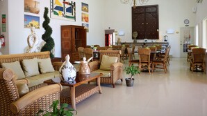 Uma sala de estar ampla com móveis de vime, um candelabro e obras de arte nas paredes.