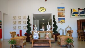 Um hall de entrada com móveis de vime, um balcão de recepção e uma parede com quadros e uma placa.