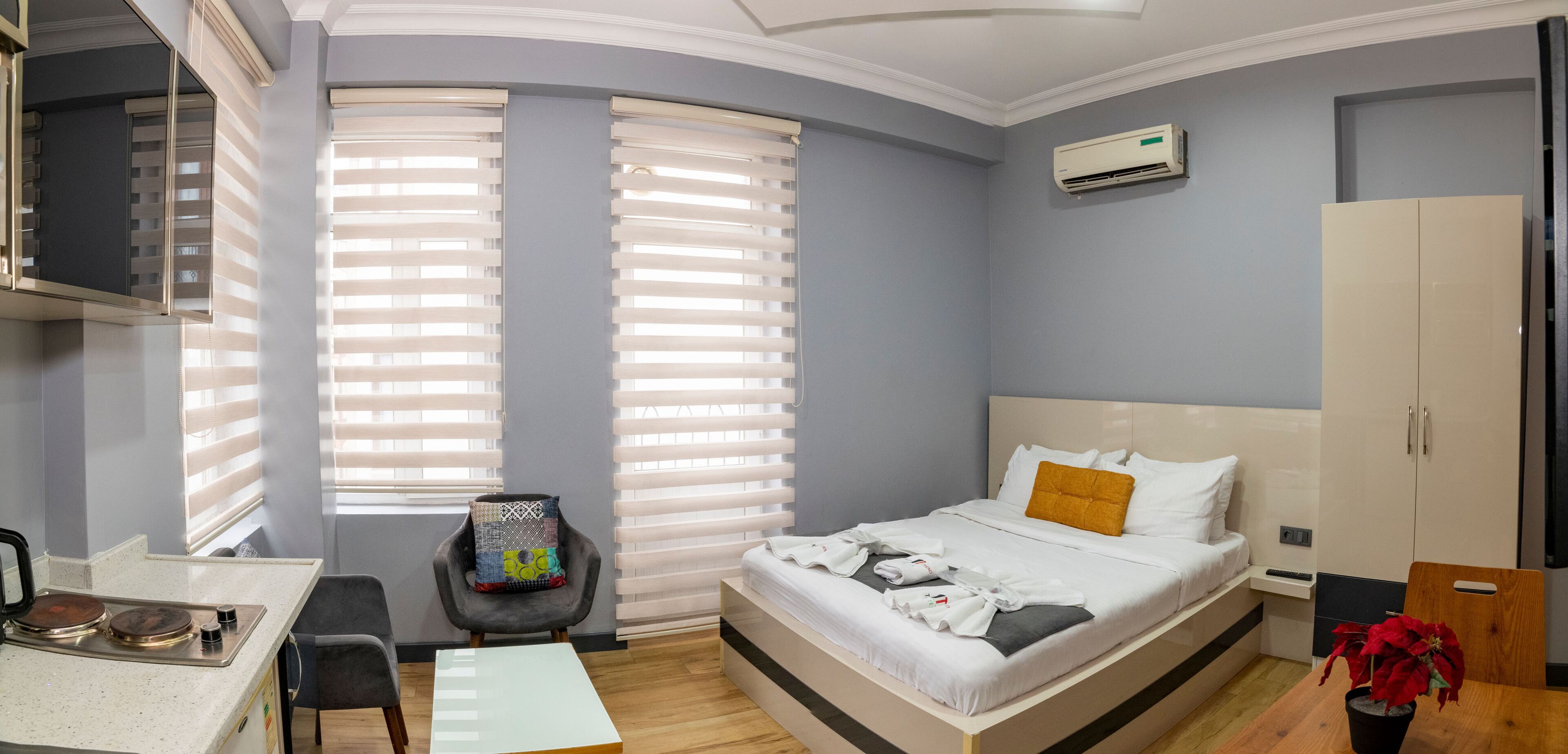 Quarto de hotel moderno com cama, escrivaninha, cadeira e mesa pequena.