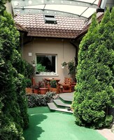 Um pátio com gramado verde, plantas em vasos e mobiliário de madeira.