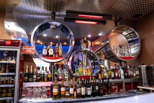 Um bar com várias garrafas de bebidas, copos e um refrigerador de Coca-Cola.