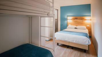 Quarto com beliche, uma cama de solteiro e cabeceira de madeira com iluminação embutida.