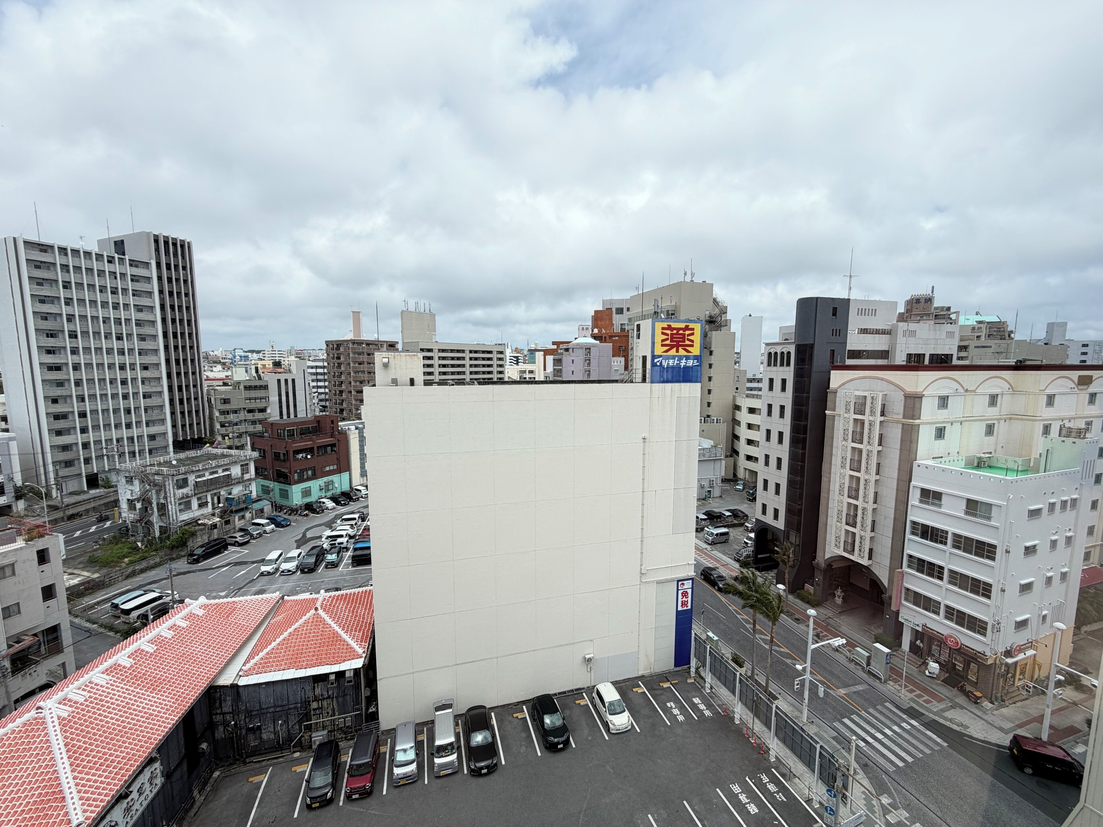 Paisagem urbana com estacionamento, edifícios e céu nublado.
