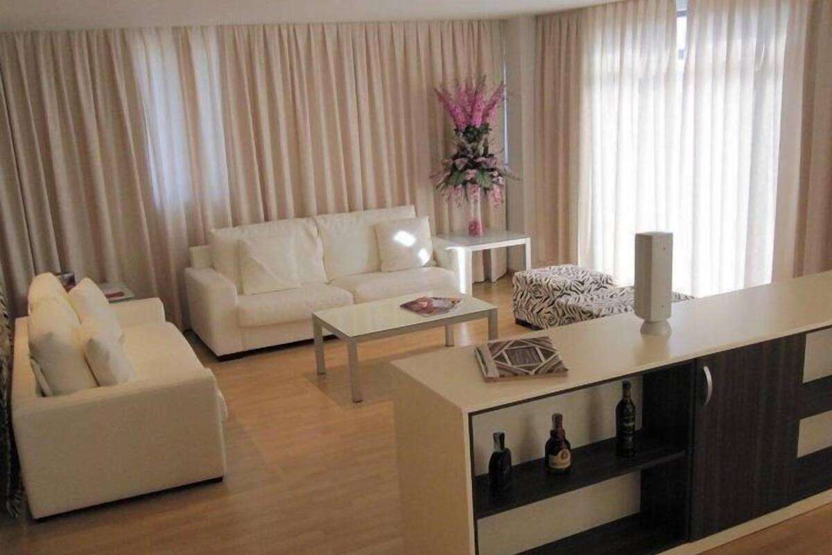 Uma sala moderna com sof á, mesa de centro e um armário com garrafas.
