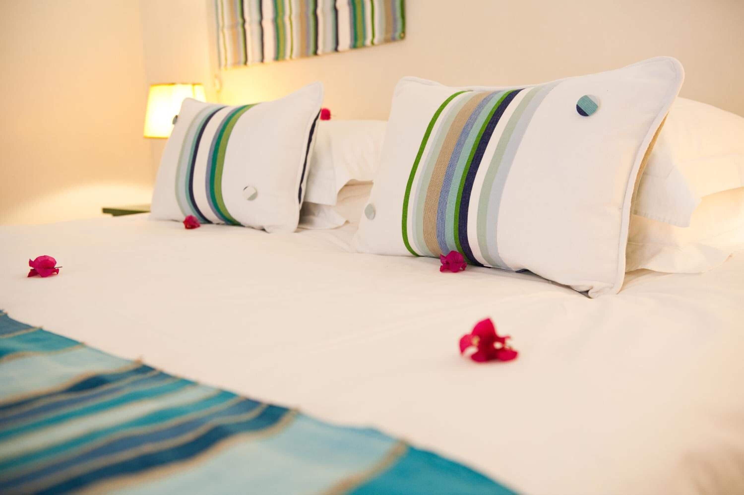 Cama bem arrumada com almofadas listradas e um cobertor azul listrado.