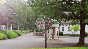 Uma passagem pavimentada com um muro de pedra e uma escultura de metal.