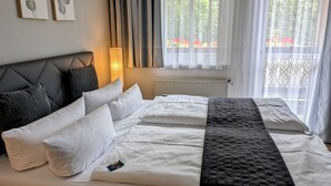 Cama bem arrumada com roupa de cama branca e preta, cabeceira e duas obras de arte na parede.