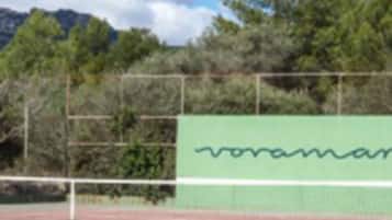 Uma quadra de tênis com cerca verde e uma placa com a inscrição 'voranmar'.