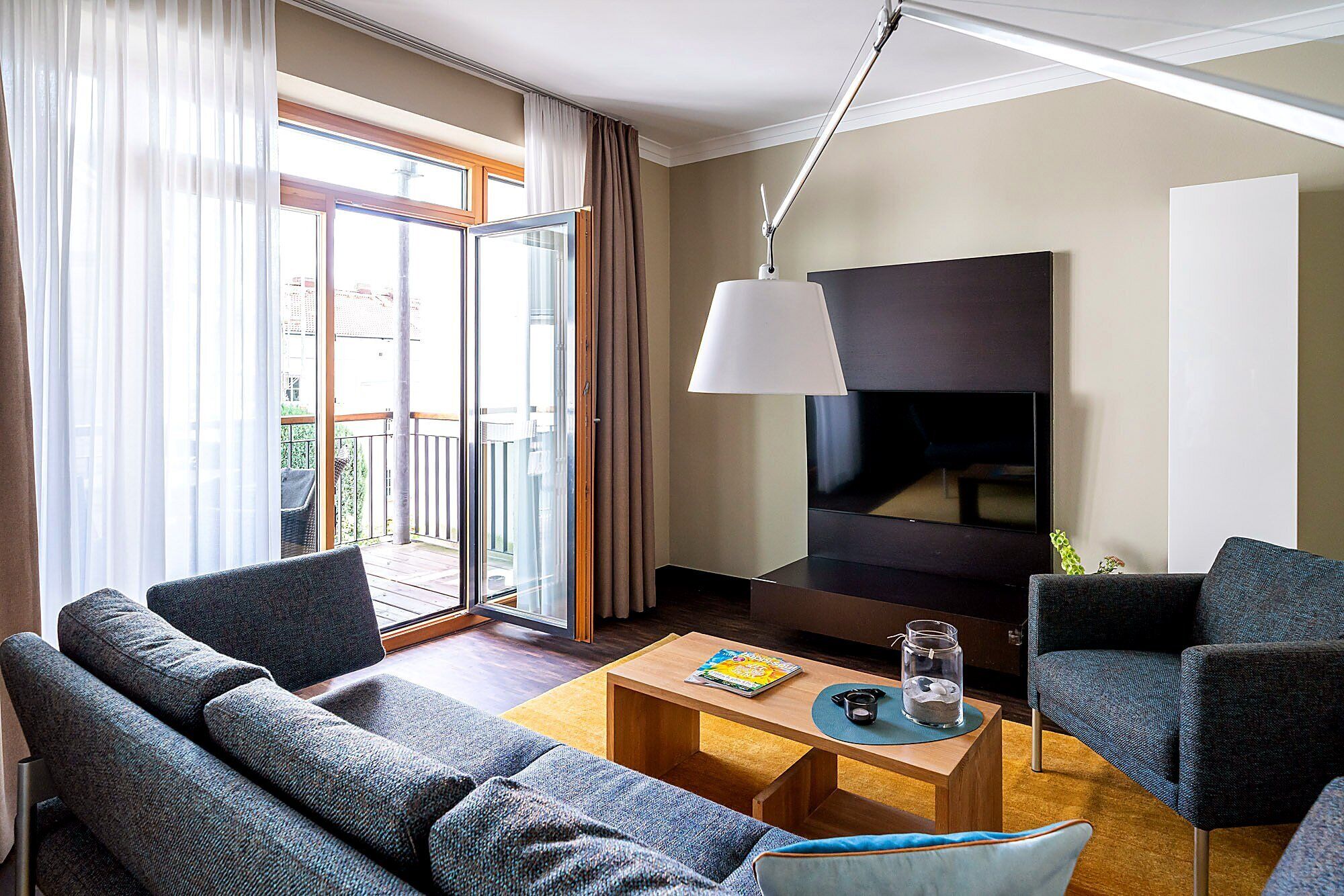 Uma sala de estar moderna com sofá, poltrona, mesa de centro e TV de tela plana.