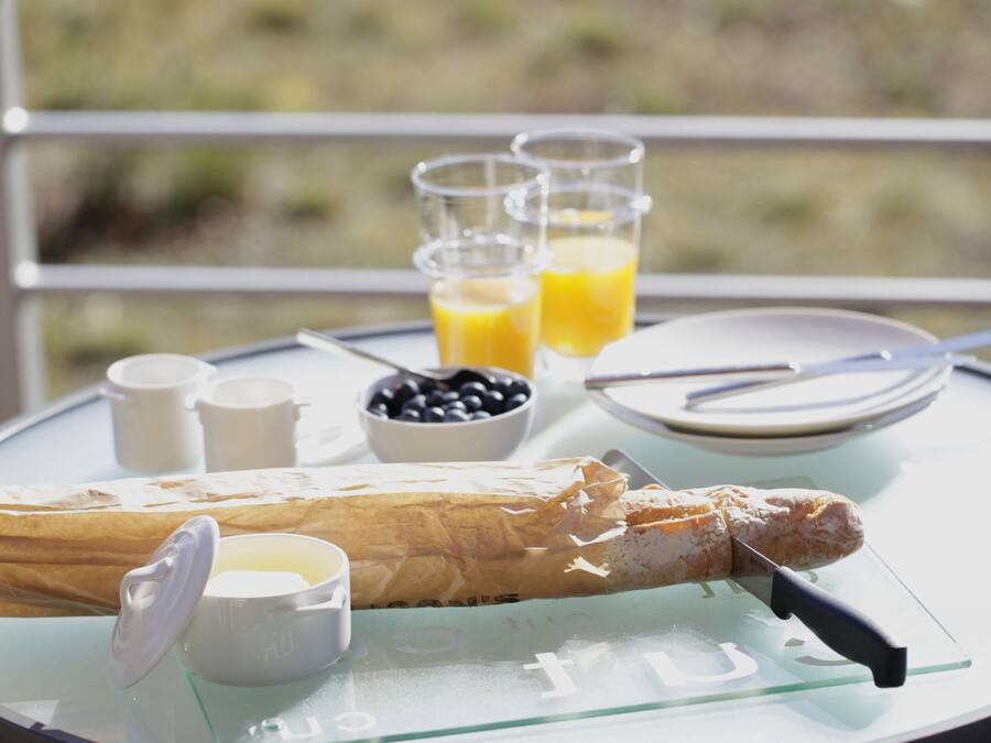 Uma mesa de café da manhã com um croissant, uma garrafa de suco, uma tigela de amoras e um copo de suco de laranja.