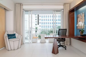 Um espaço de escritório moderno com uma janela grande, uma mesa, uma cadeira e uma pequena mesa.