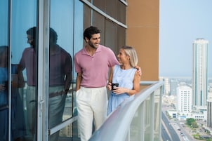 Um homem e uma mulher em uma varanda, com vista para a cidade.