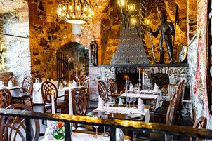 Um restaurante com paredes de pedra, mesas e cadeiras de madeira.