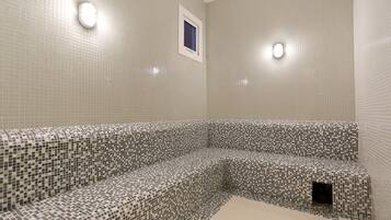 Um espaço revestido com azulejos, com um banco e duas luzes fixadas na parede.