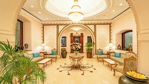 Um lobby luxuoso com decoração requintada, um imponente candelabro e áreas de estar confortáveis.