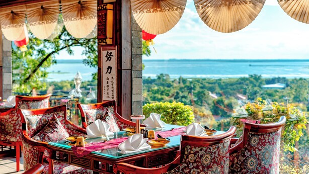 Um restaurante com decoração tradicional, mesas ao ar livre e vista para o oceano.
