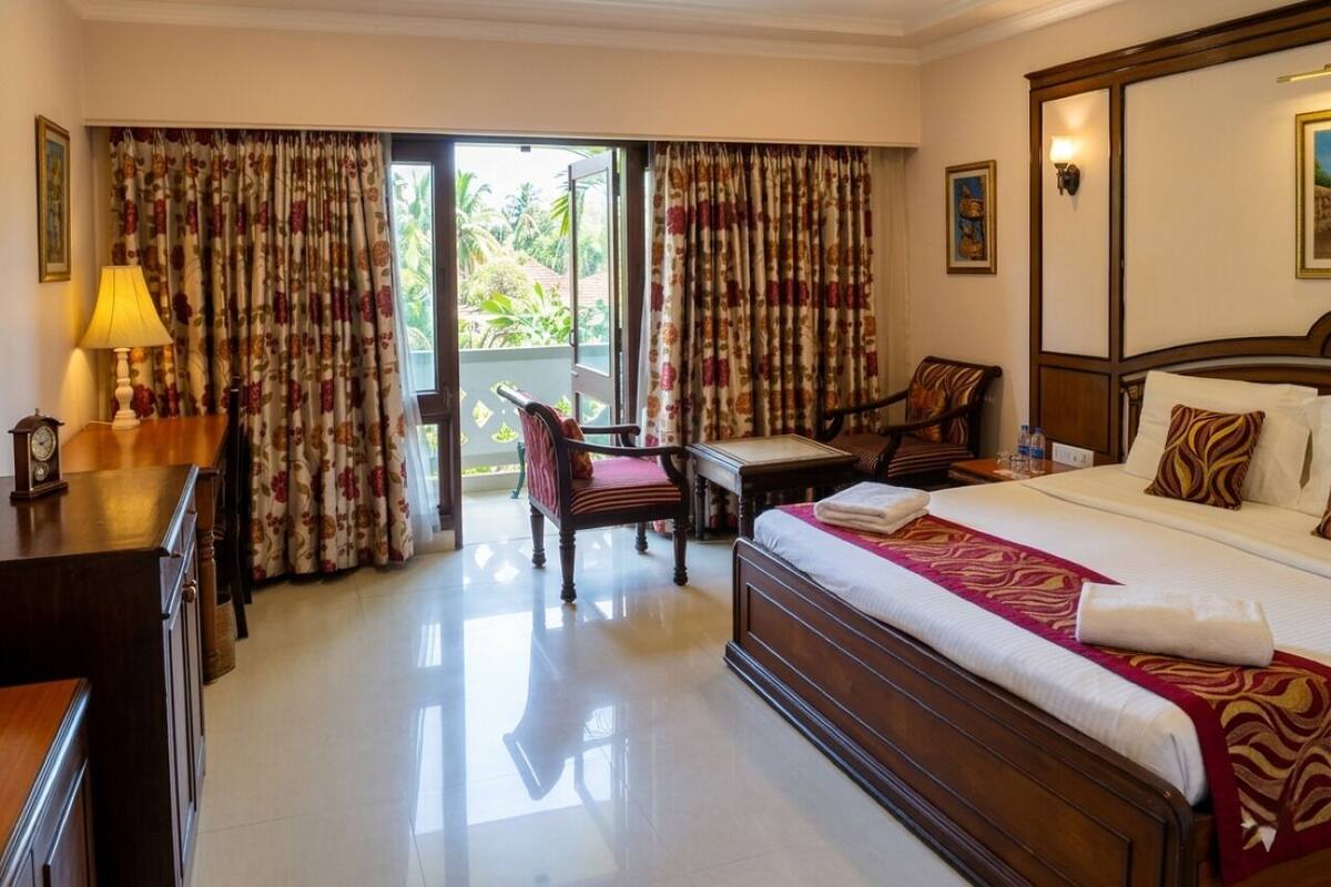 Quarto de hotel com cama, escrivaninha, cadeira e vista para o exterior.