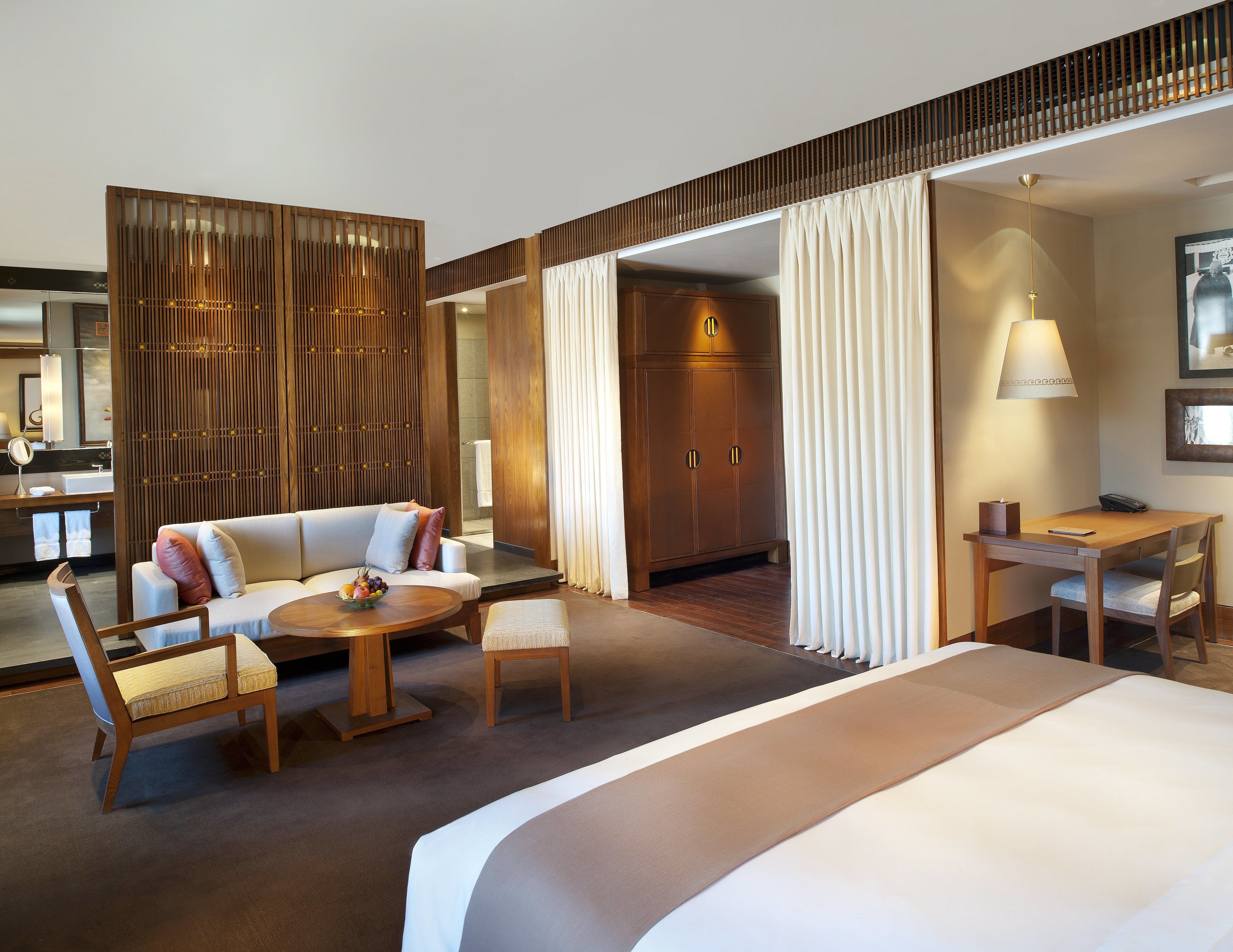 Quarto de hotel com uma cama grande, um sofá, uma mesa de jantar e uma área de banheiro separada.
