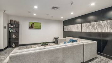Uma sala de estar moderna com um sofá modular cinza, uma estante, uma moldura com a imagem de um cavalo e um painel decorativo na parede.