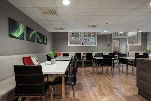 Uma sala de conferências moderna com uma mesa branca, cadeiras pretas e um sofá cinzento.