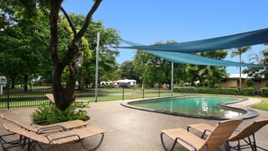 Uma área à beira da piscina com espreguiçadeiras, um toldo e piscina.