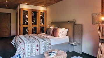Um quarto com cama, mesa de cabeceira, luminária e uma pequena mesa redonda com livros.