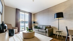 Uma sala de estar moderna com sofá, mesa de centro, luminária e vista da cidade através de amplas janelas.