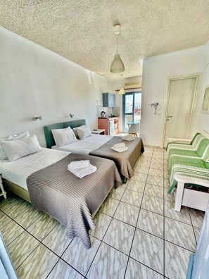 Quarto de hotel com duas camas, uma escrivaninha, uma cadeira e vista para o exterior.