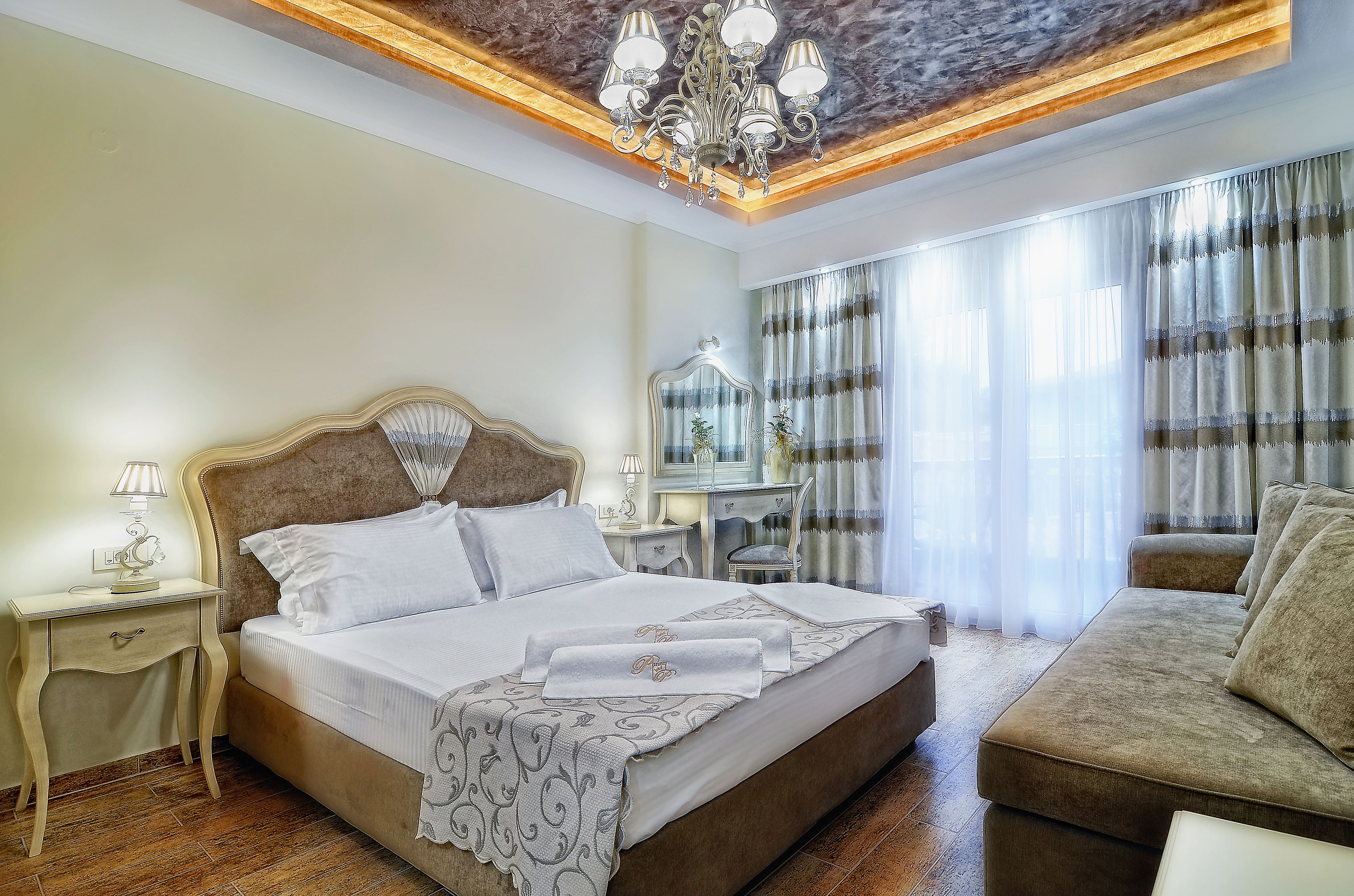 Quarto bem equipado com uma cama grande, mesa de cabeceira, espelho e sofá.