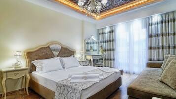 Quarto bem equipado com uma cama grande, mesa de cabeceira, espelho e sofá.