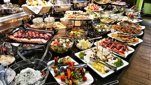 Um buffet com diversos alimentos e utensílios.