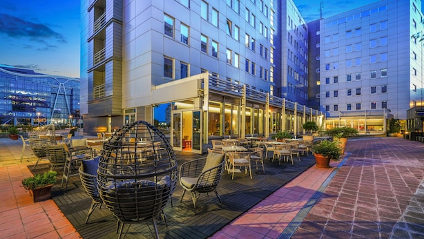Um hotel moderno com área externa para sentar e fachada de vidro.