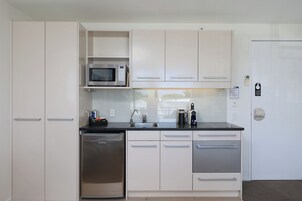 Uma cozinha moderna com armários brancos, micro-ondas, lava-louças e frigorífico.