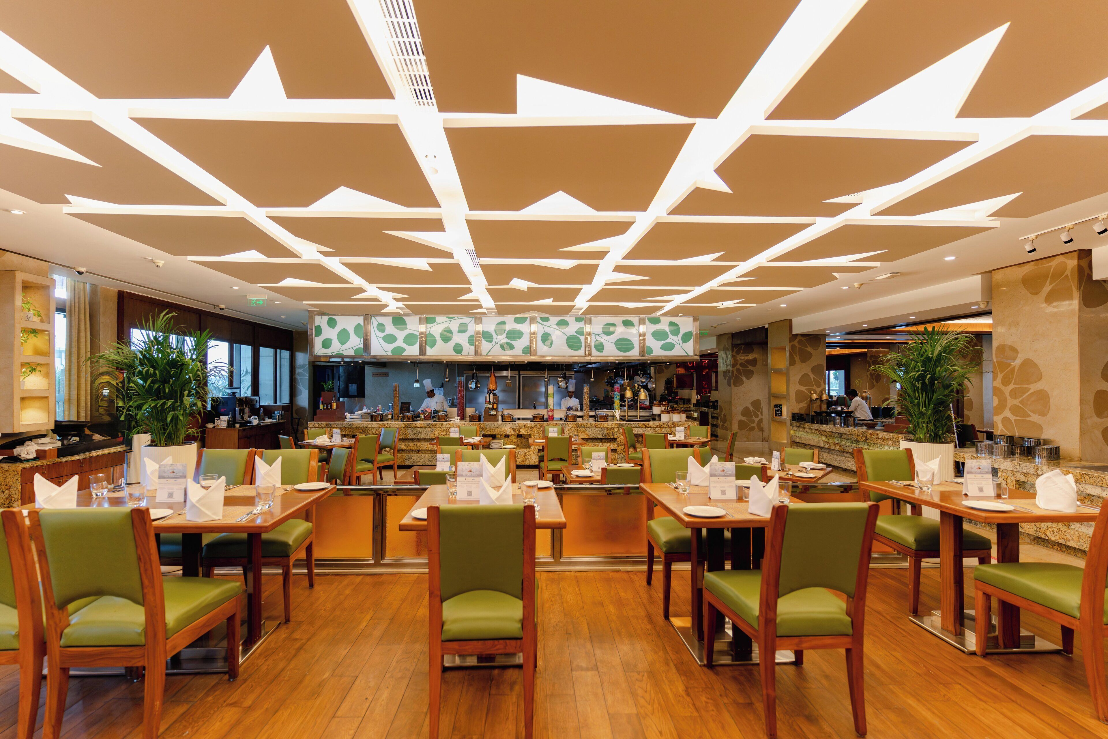 Um restaurante com design moderno no teto, mesas e cadeiras de madeira e um espaço bar.
