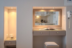 Casa de banho compacta com espelho, secador de cabelo e um pequeno banquinho.