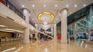 Um hall amplo com um lustre central, vários andares e um balcão de recepção.