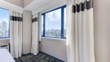 Quarto de hotel com uma janela grande, uma cama e um tapete estampado.