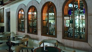 Um restaurante com janelas em arco, mesas e cadeiras.