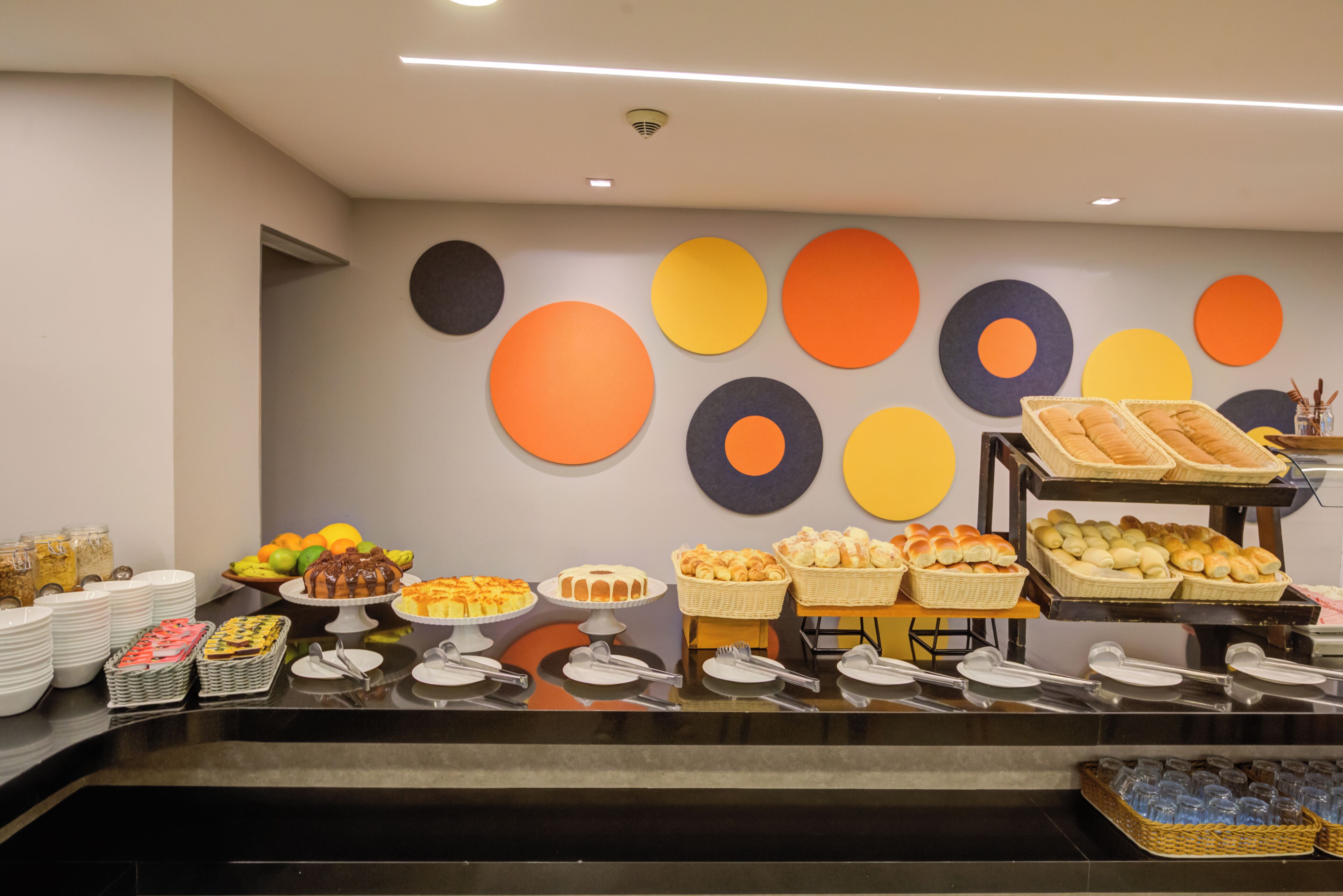 Buffet com diversos alimentos e uma parede decorada com círculos coloridos.