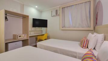 Quarto de hotel com duas camas, uma escrivaninha, televisão, mini-frigorífico e janela com cortinas.