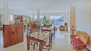 Uma sala de jantar espaçosa com vista para um lago e montanhas.