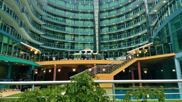 Um hotel com vários andares e fachada curva, área de estar ao ar livre e uma escadaria central.